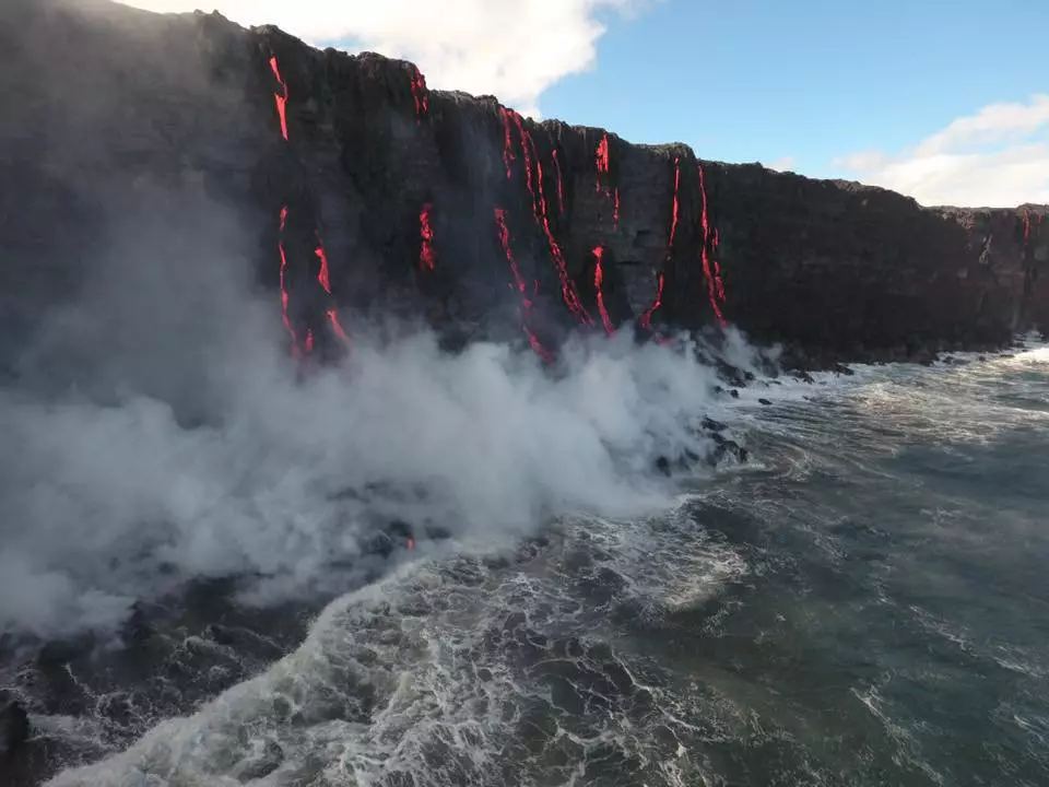 Surfingist rullet ved siden av spewing vulkanen